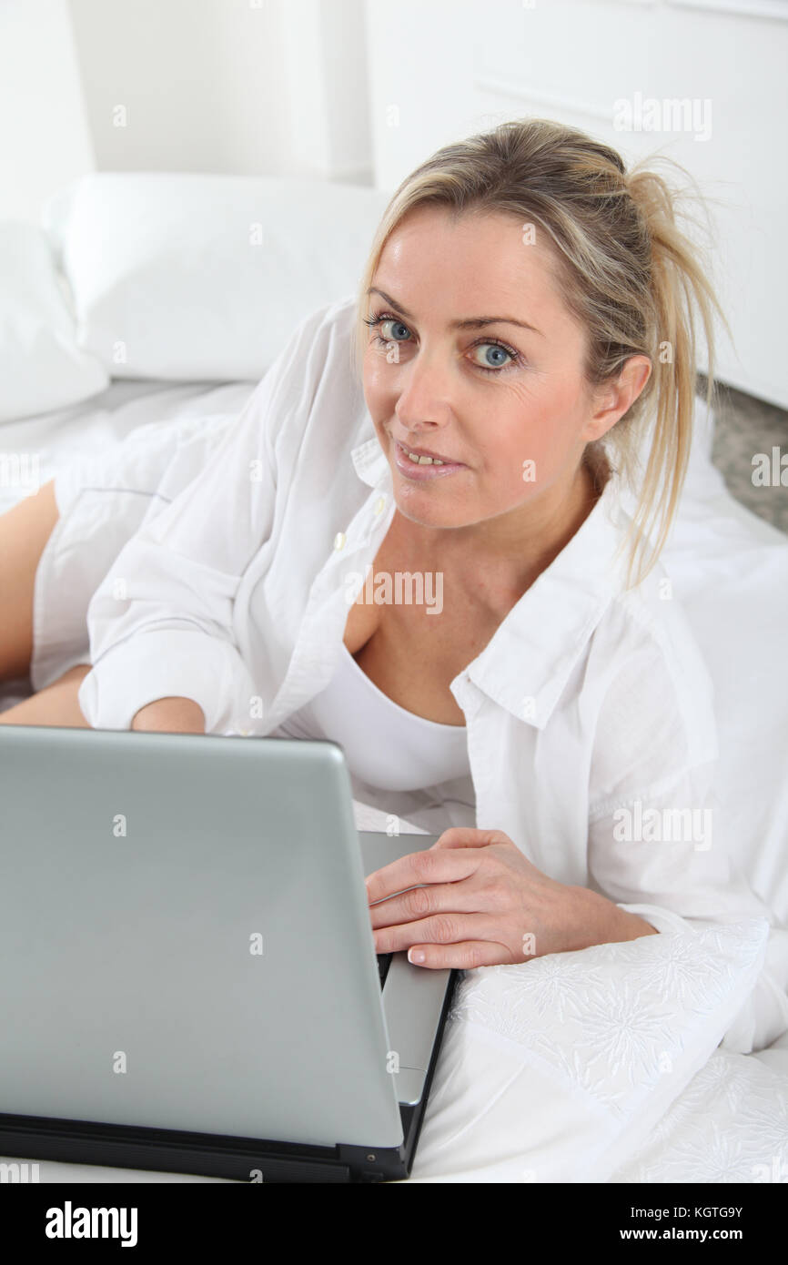 Blond woman with laptop computer in bed Stock Photo - Alamy