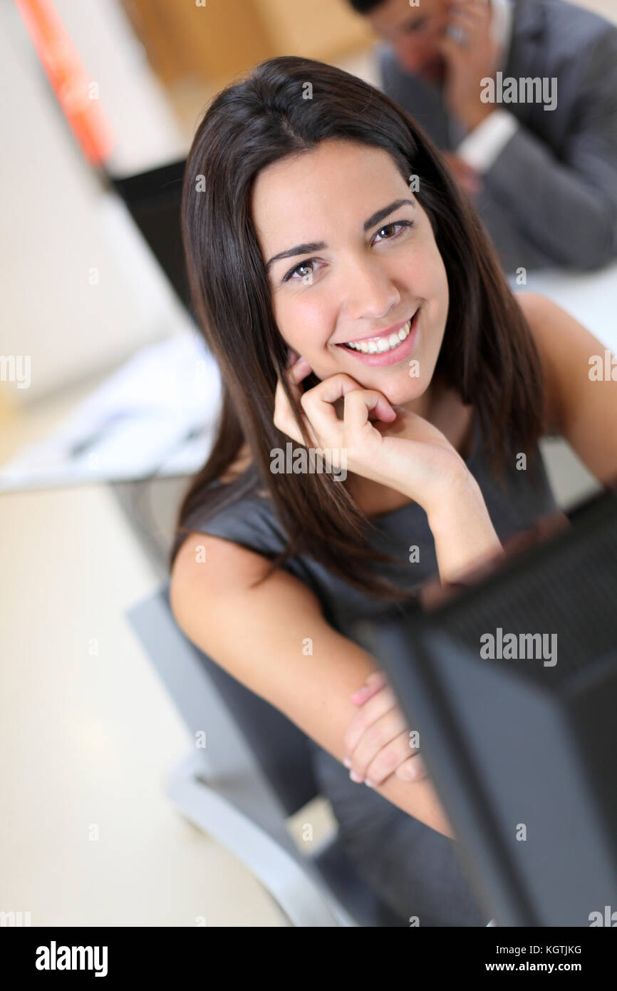 Smiling secretary sitting at her desk Stock Photo - Alamy