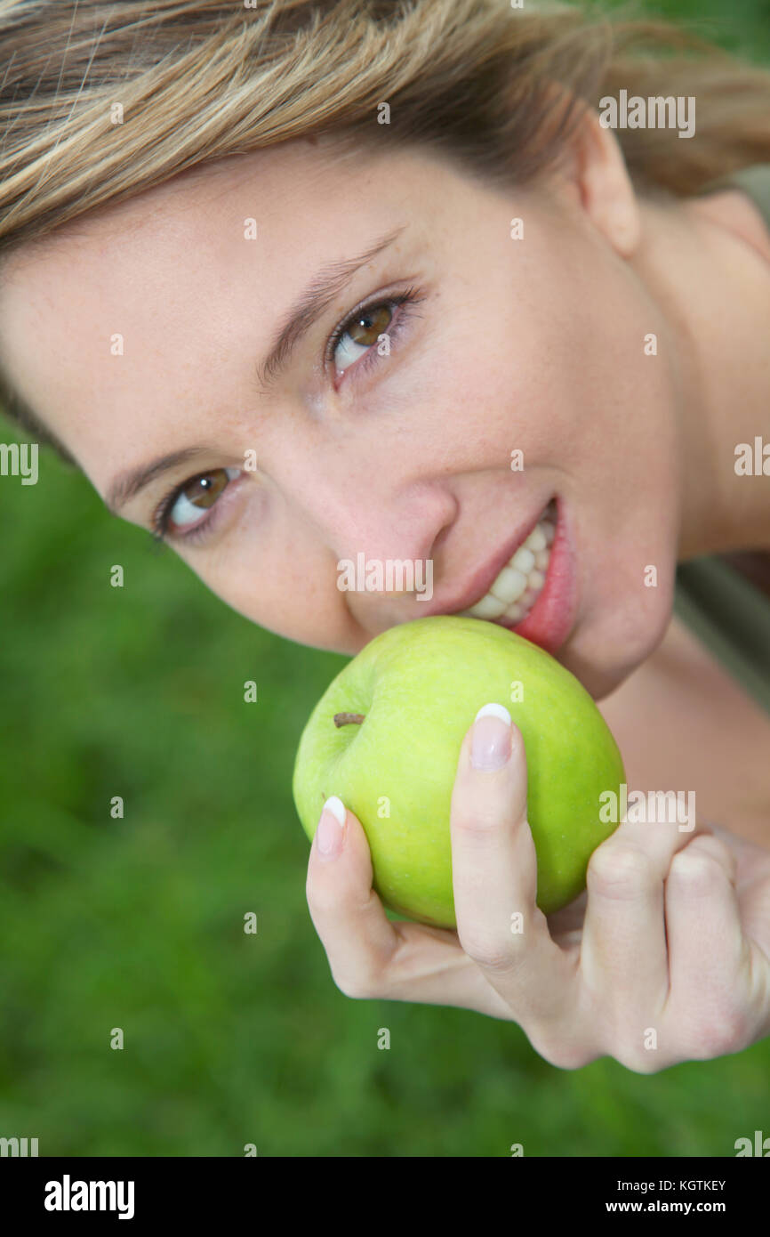 Portrait of woman eating green apple Stock Photo - Alamy