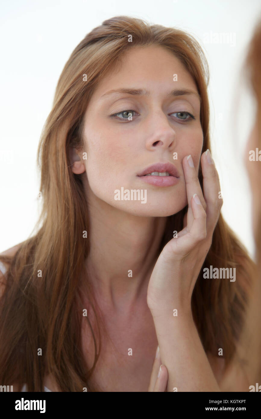 Beautiful woman looking in a mirror Stock Photo - Alamy