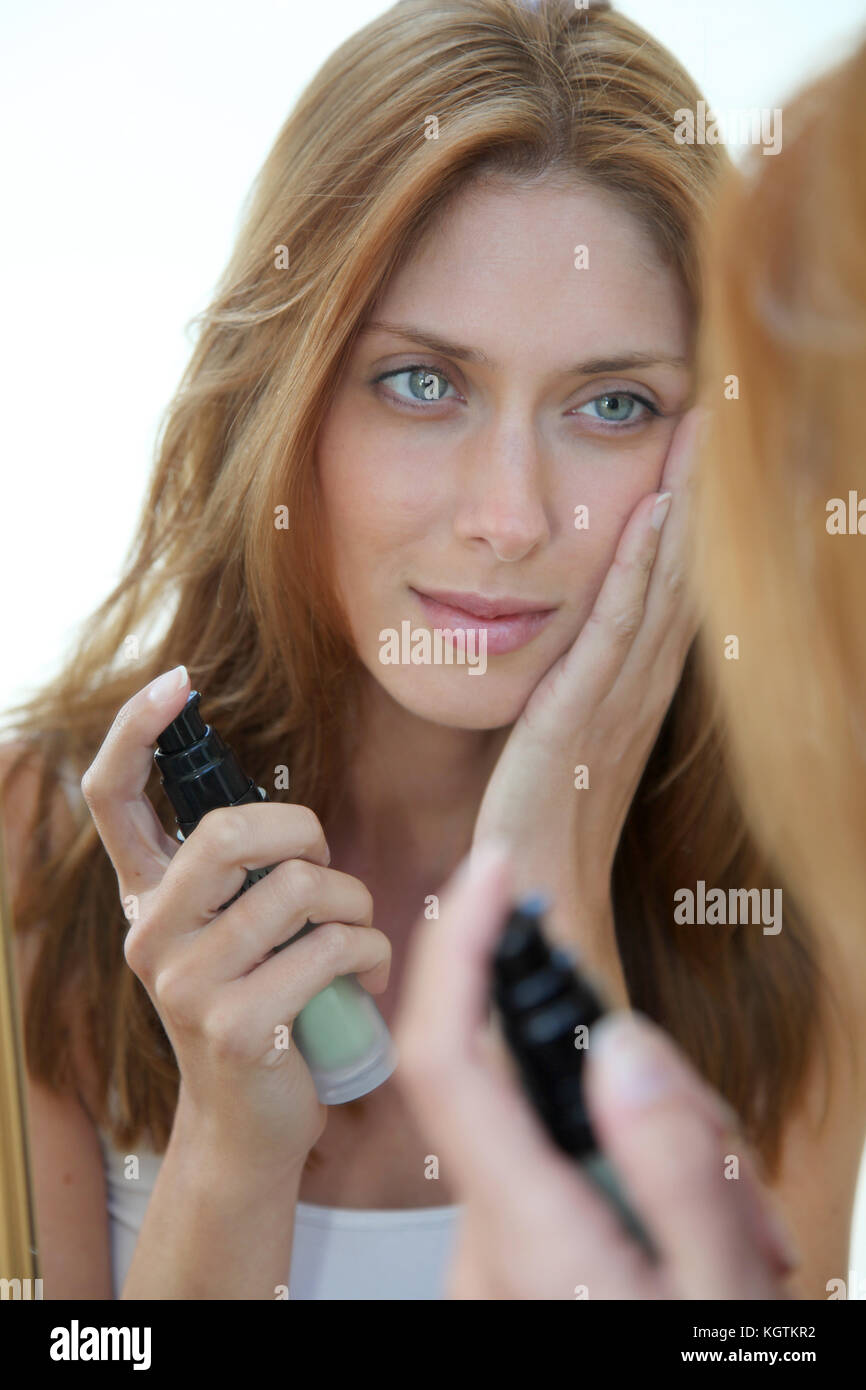 Beautiful woman putting foundation on her face Stock Photo - Alamy