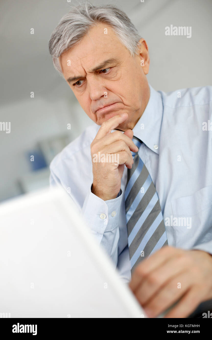 Senior man with puzzled look in front of laptop Stock Photo - Alamy
