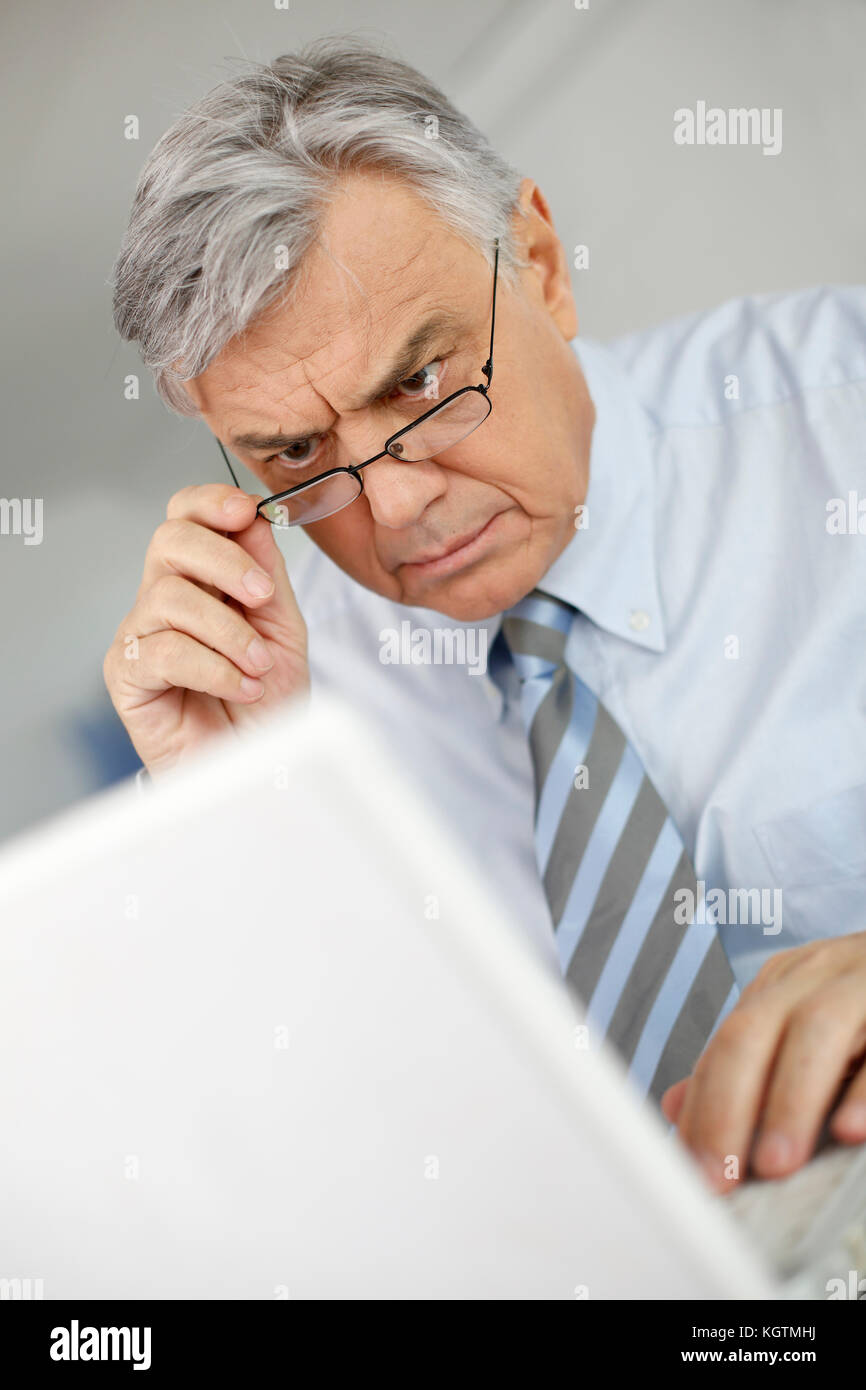Portrait of businessman with perplexed look in front of laptop Stock ...