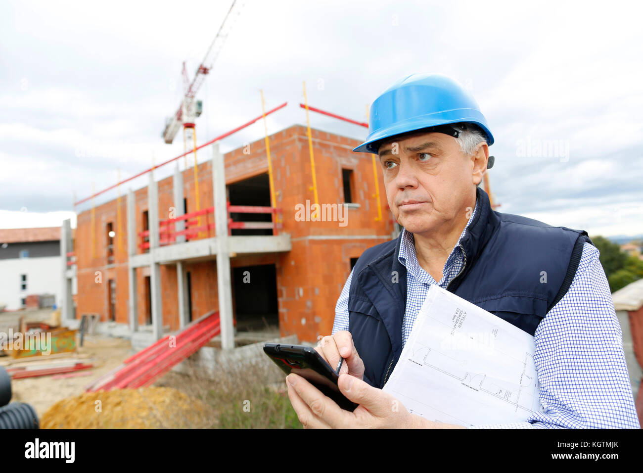 Construction manager on building site using smartphone Stock Photo - Alamy