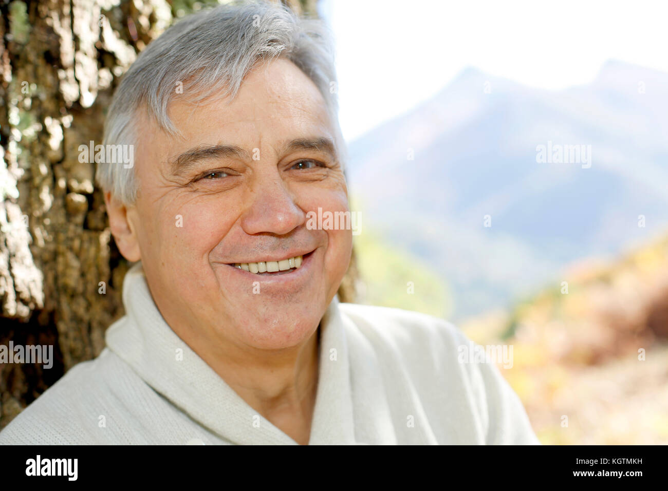 Portrait of smiling senior man leaning against tree Stock Photo - Alamy
