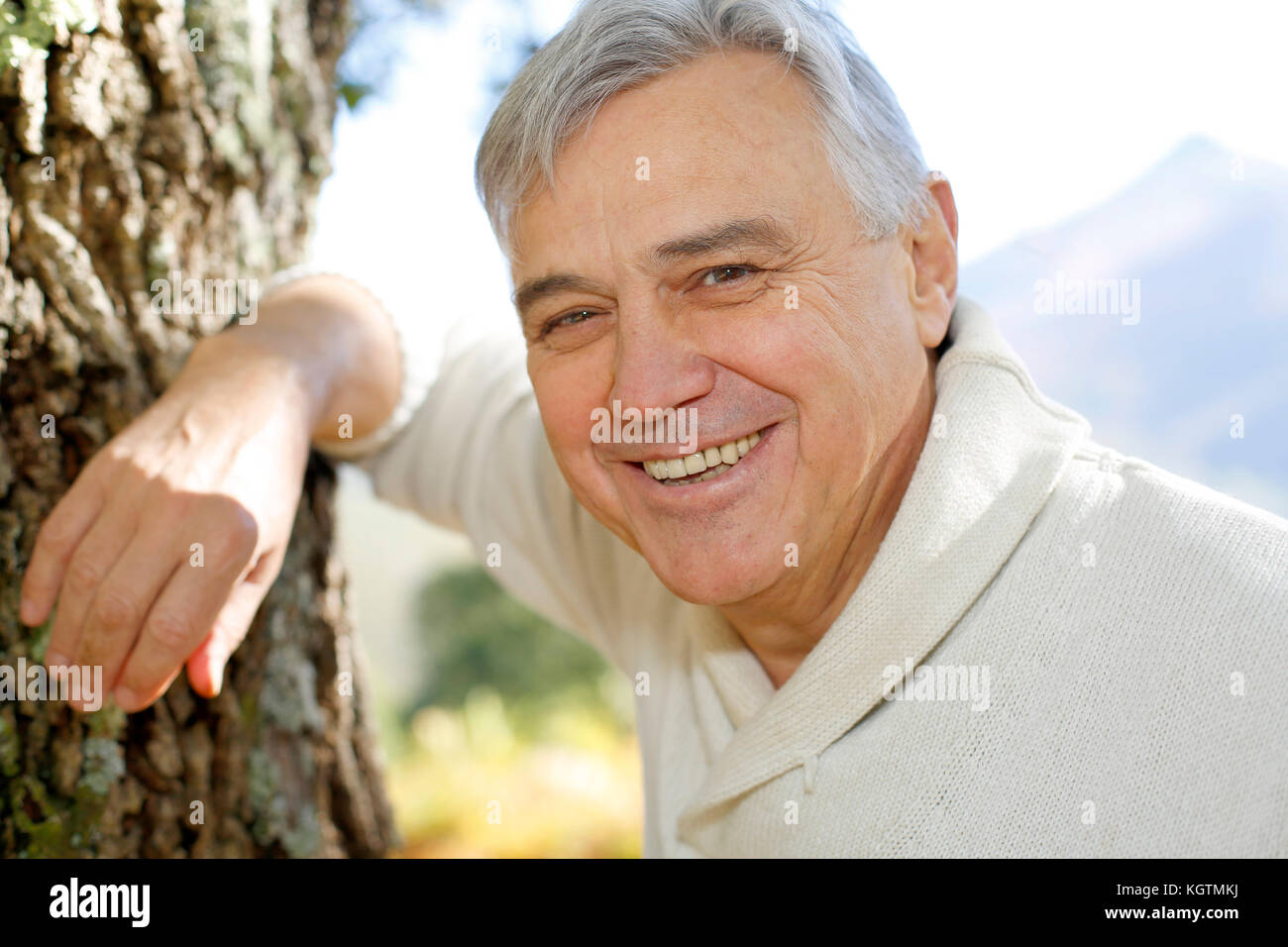 Senior man leaning against tree hi-res stock photography and images - Alamy