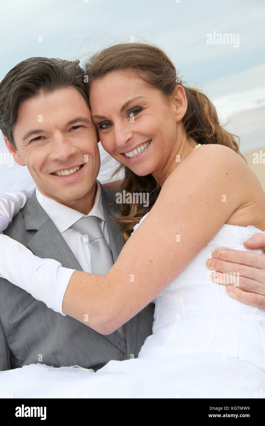 Groom holding bride in his arms at the beach Stock Photo - Alamy