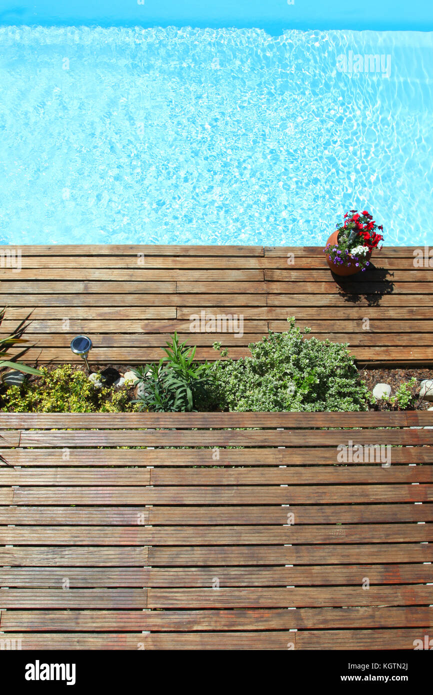 View of swimming pool with teck wood flooring Stock Photo - Alamy