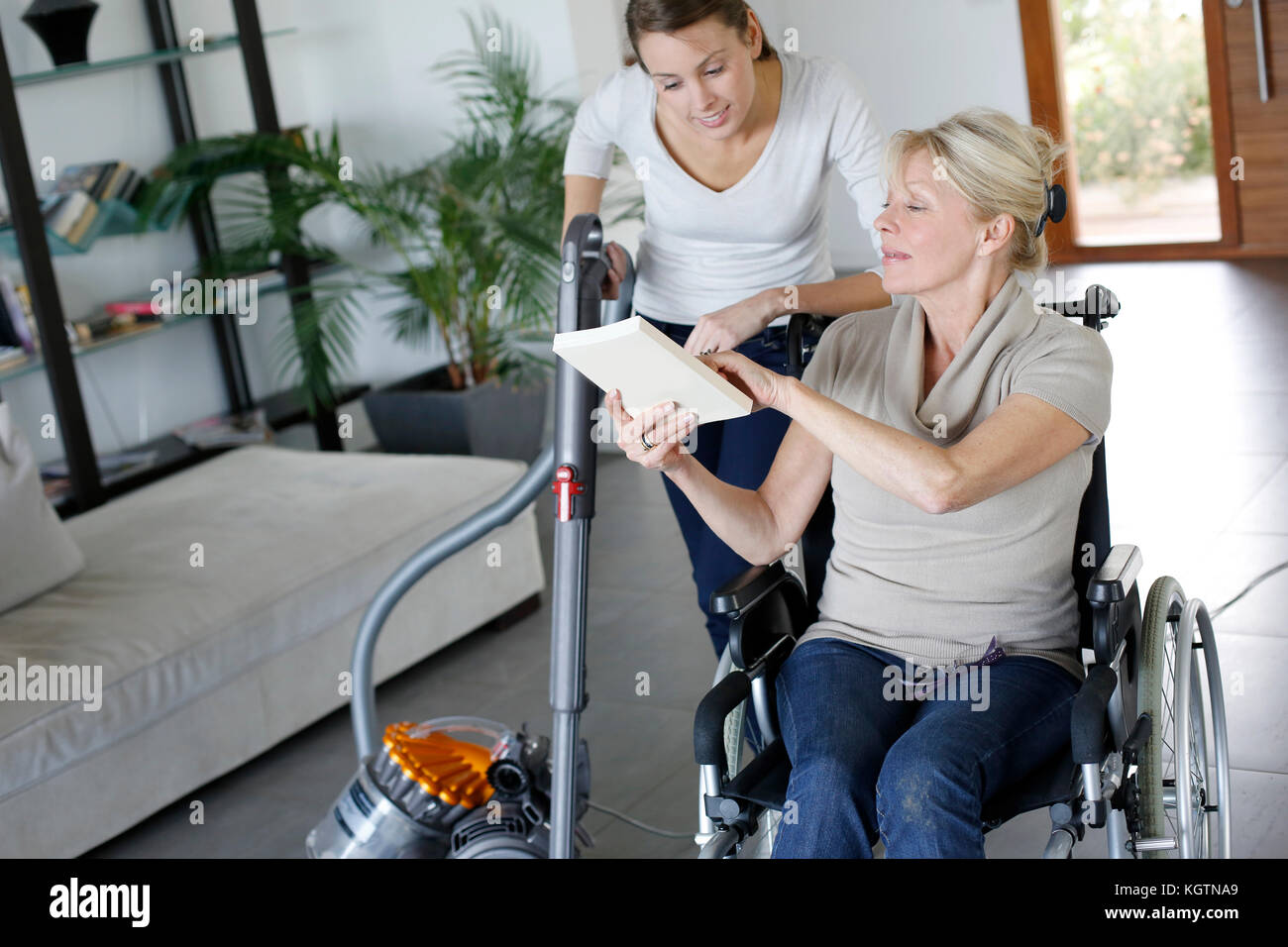 Young woman helping disabled lady at home Stock Photo - Alamy