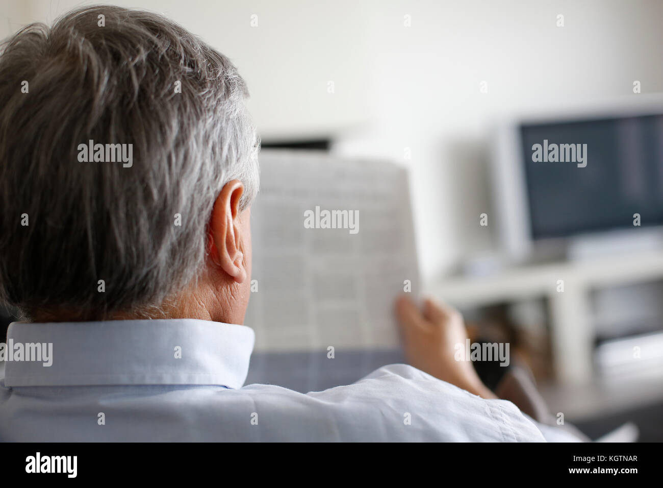 Back view of man reading newspaper at home Stock Photo - Alamy
