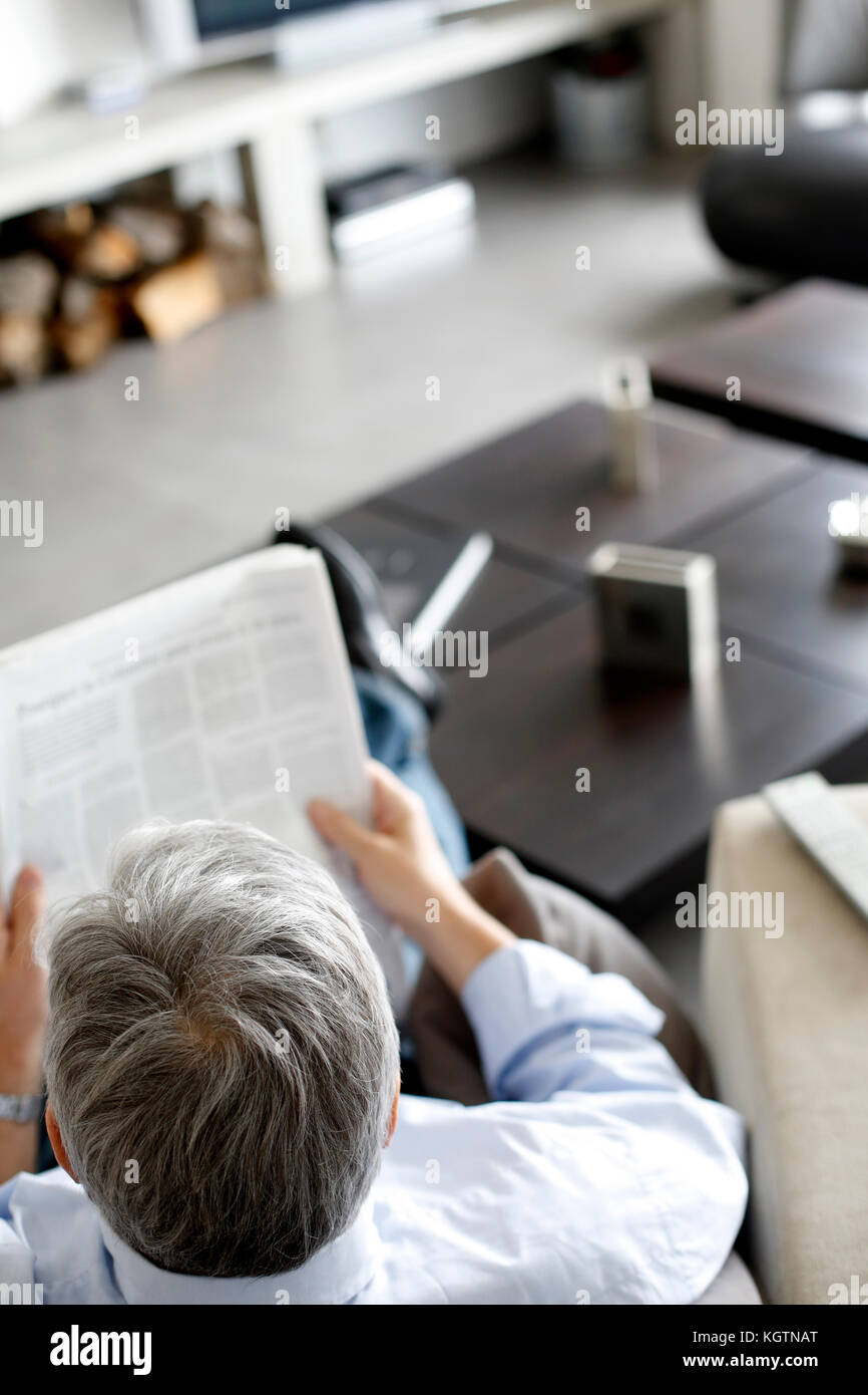 Back view of man reading newspaper at home Stock Photo - Alamy