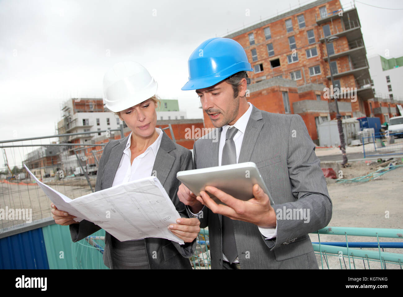 Construction engineers checking plan on building site Stock Photo - Alamy