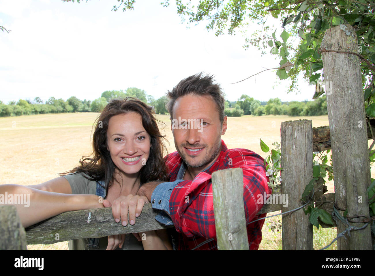 Couple leaning on fence in country field Stock Photo - Alamy