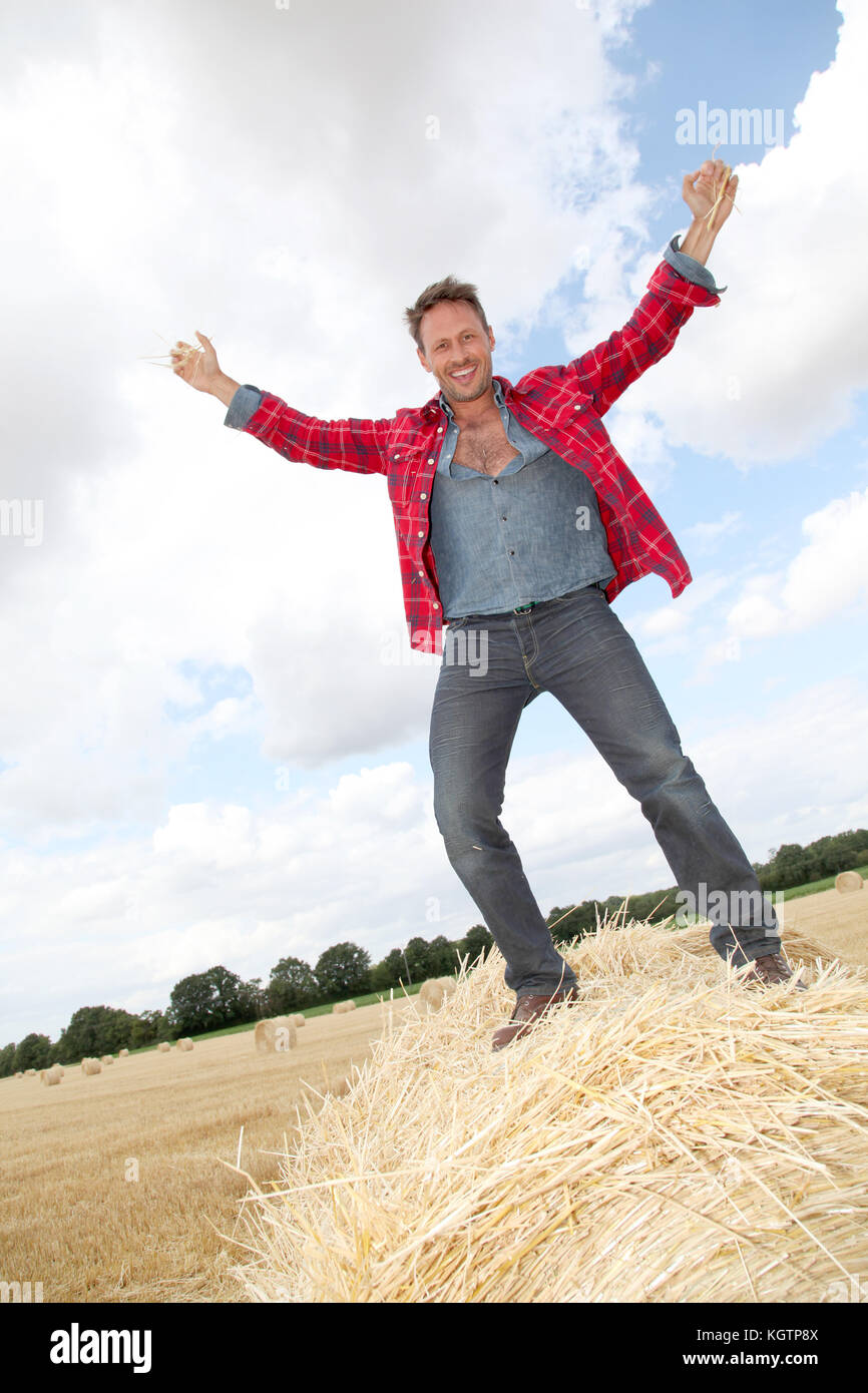 Handsome man standing on a hay bale Stock Photo - Alamy