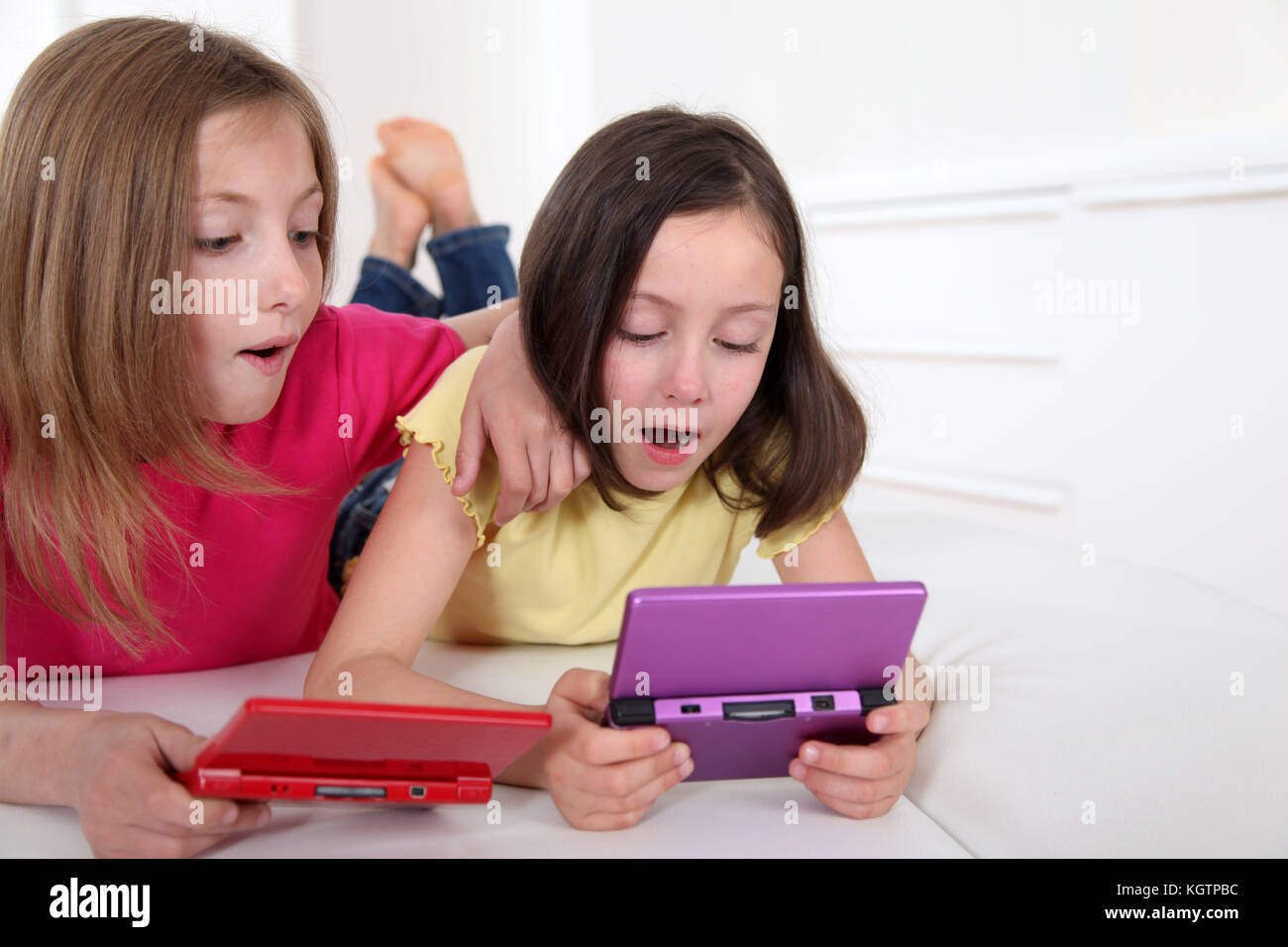 Young girls playing with gaming console on sofa Stock Photo - Alamy