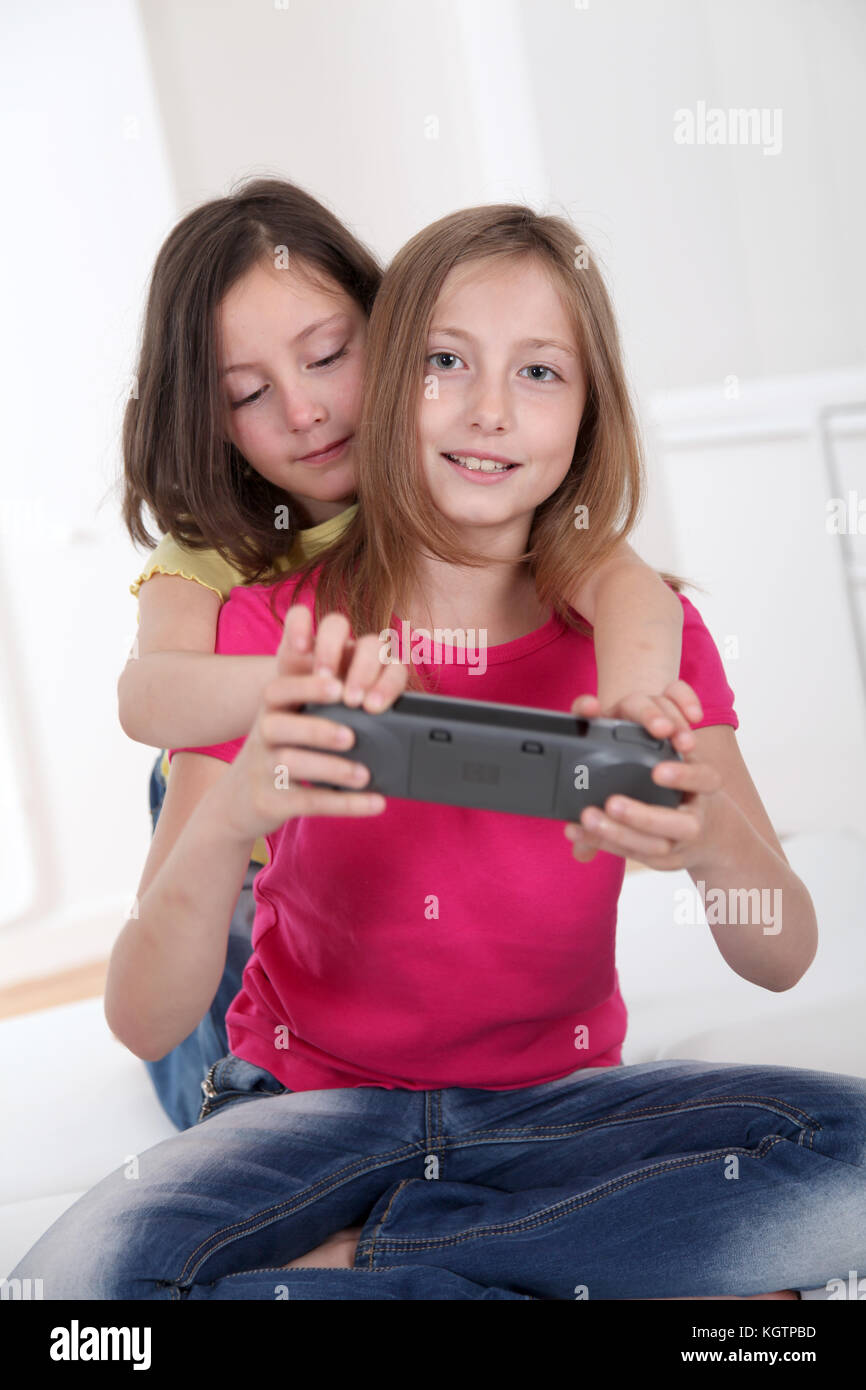 Young girls playing with gaming console on sofa Stock Photo - Alamy