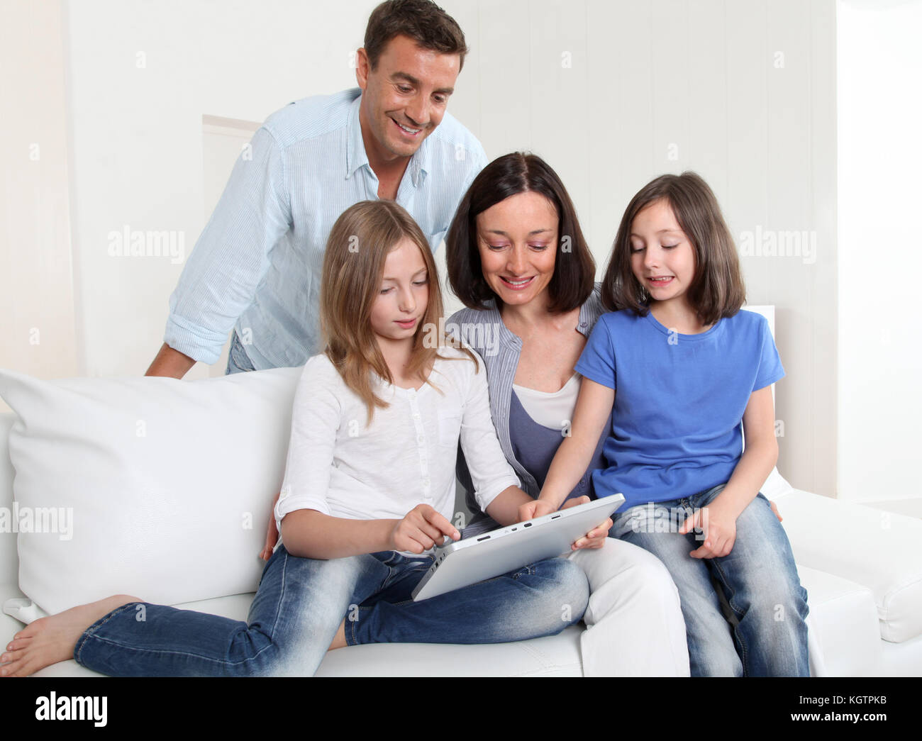 Parents and children using electronic tablet at home Stock Photo - Alamy
