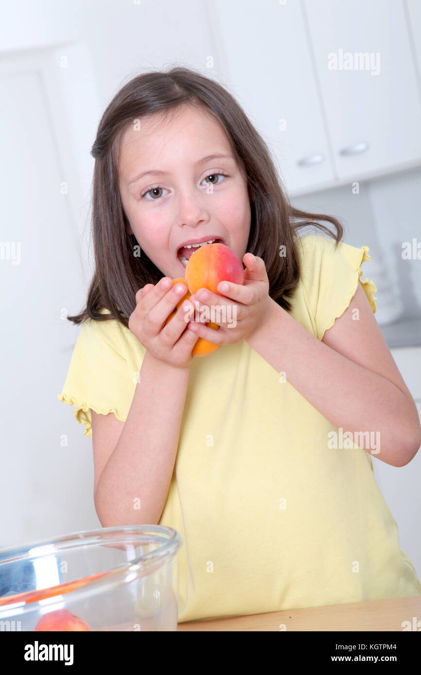 Portrait of little girl eating apricots Stock Photo - Alamy