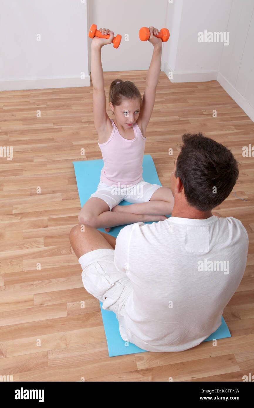 Man helping young girl with fitness exercises Stock Photo - Alamy