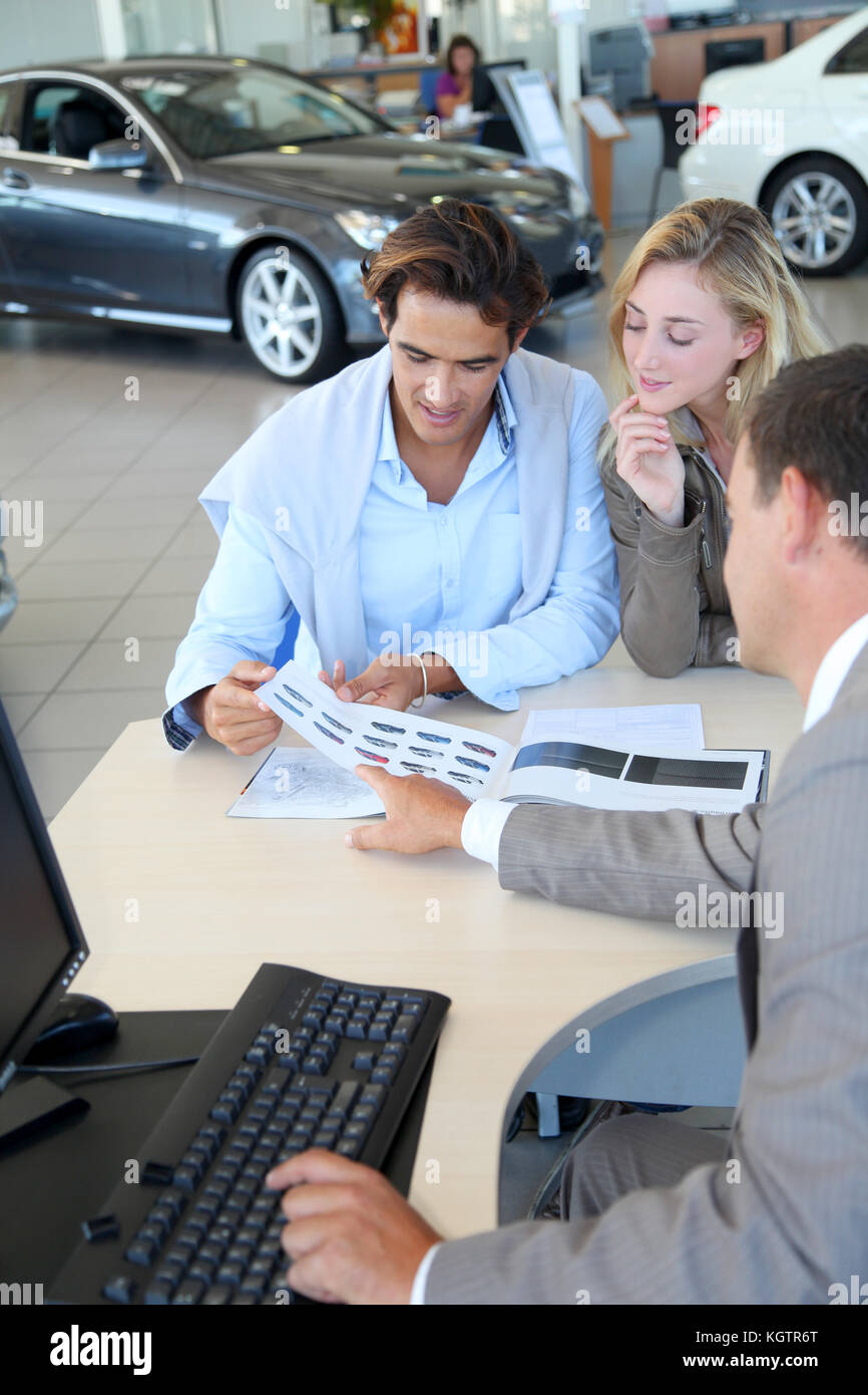 Car seller and couple looking at catalogue Stock Photo - Alamy