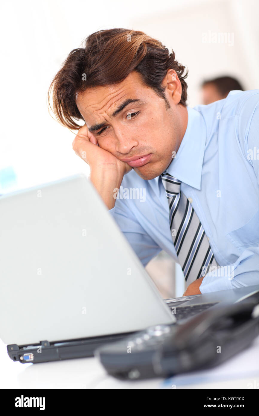 Businessman with tired look at work Stock Photo - Alamy