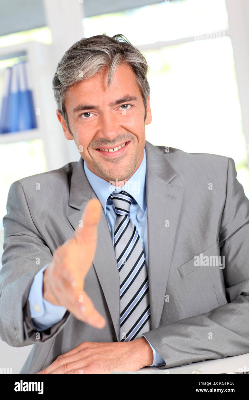 Businessman giving handshake to client Stock Photo - Alamy