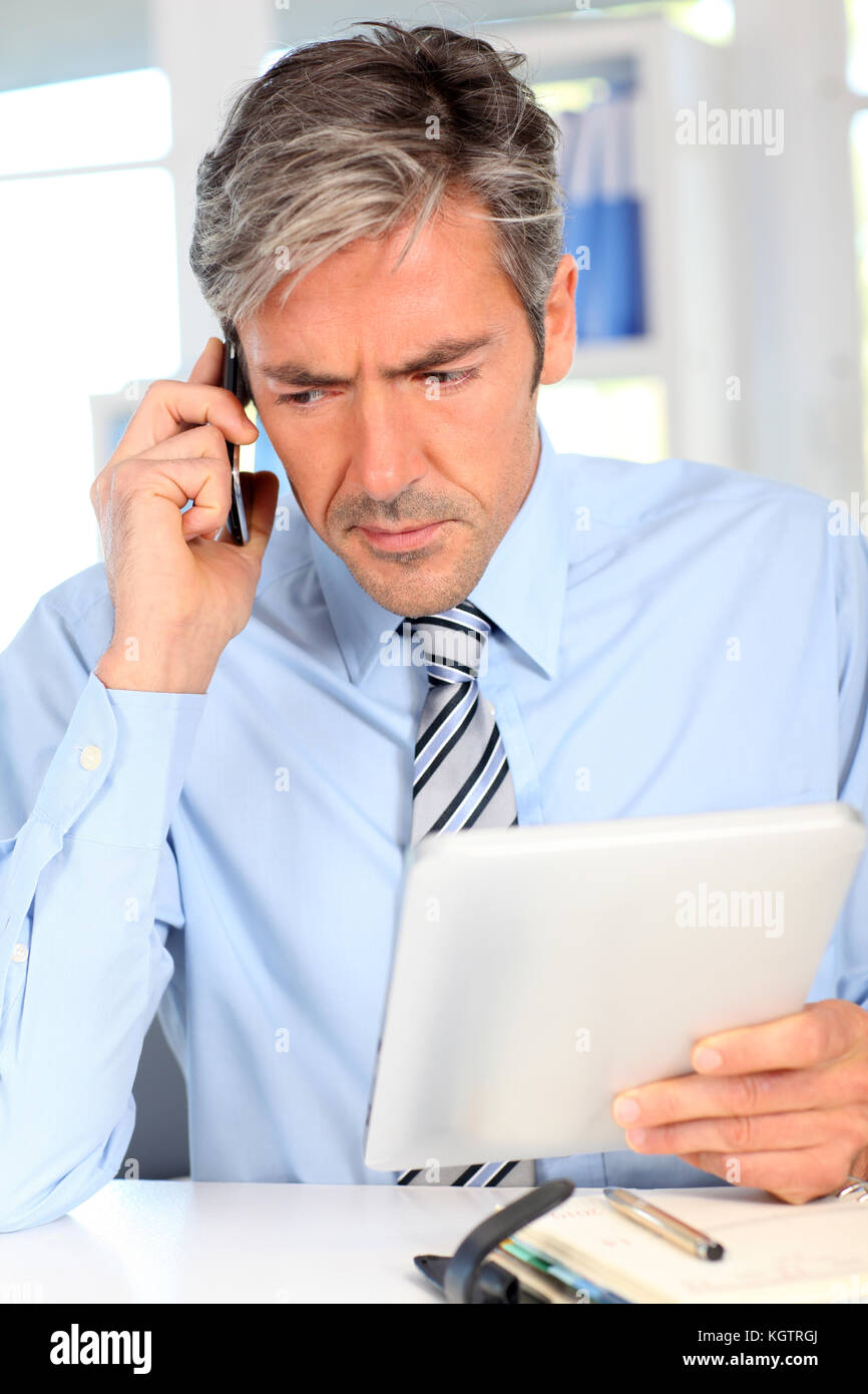 Manager in office talking on mobile phone Stock Photo - Alamy