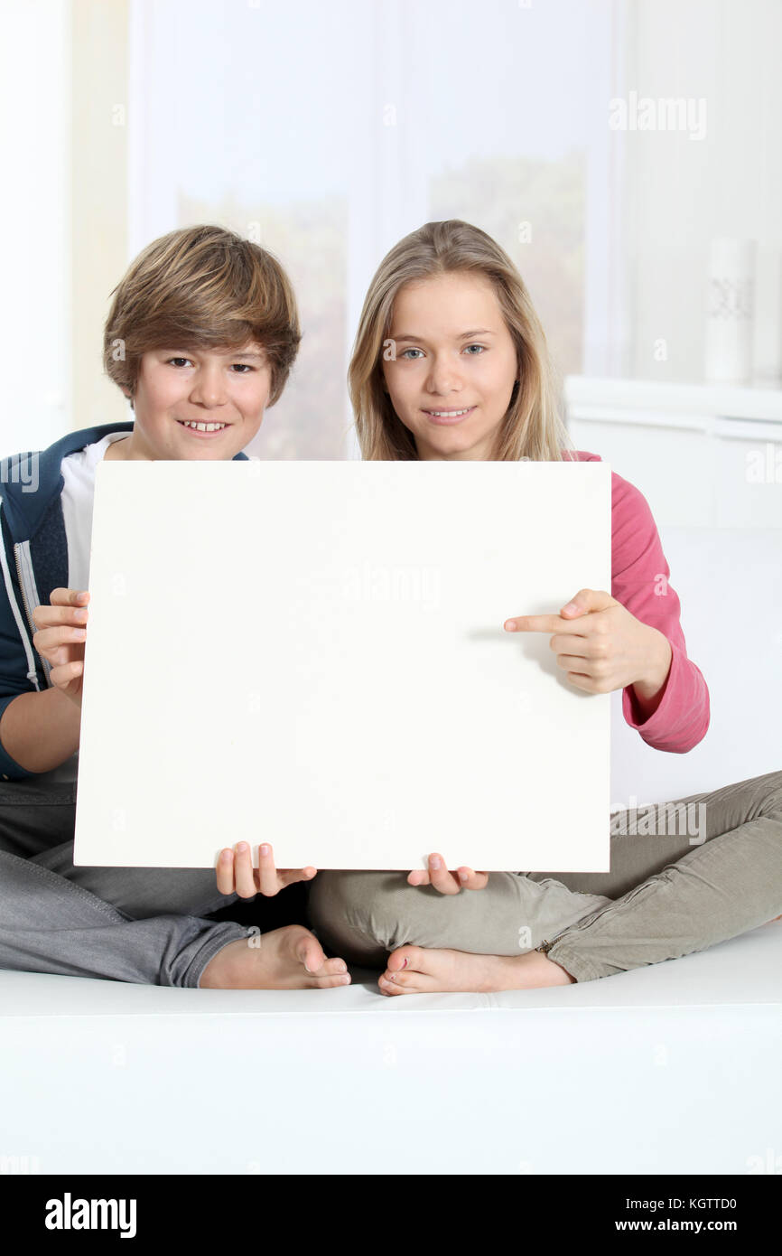 Smiling teenagers sitting in sofa with whiteboard Stock Photo - Alamy