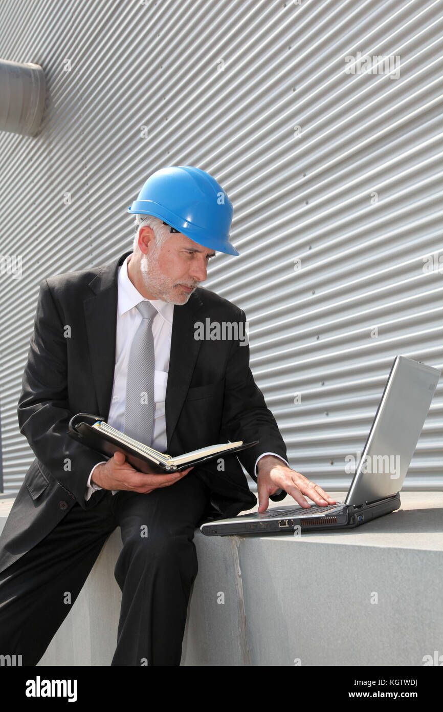 Site manager checking planning on computer Stock Photo - Alamy