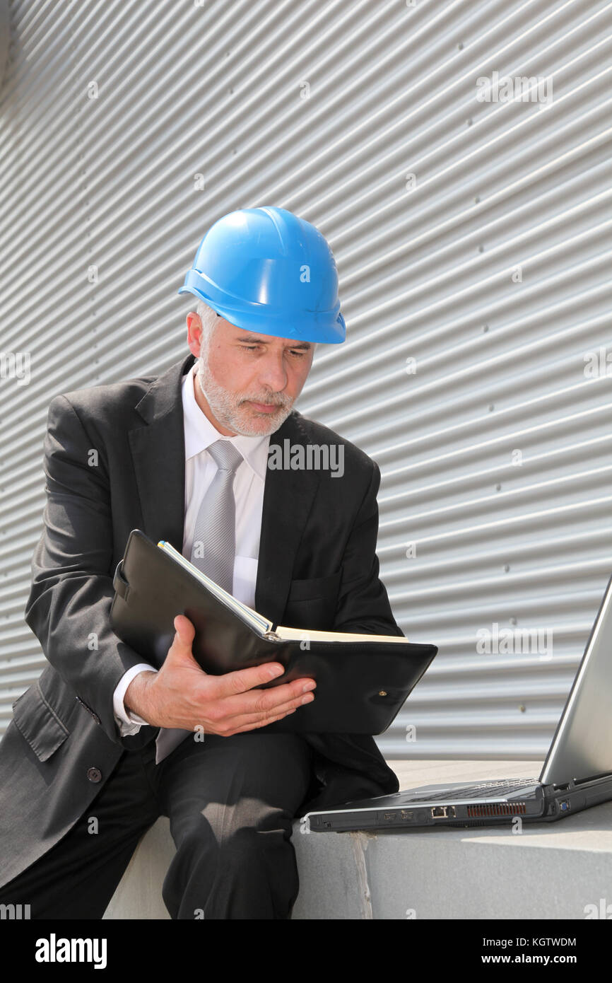 Site manager checking planning on computer Stock Photo - Alamy