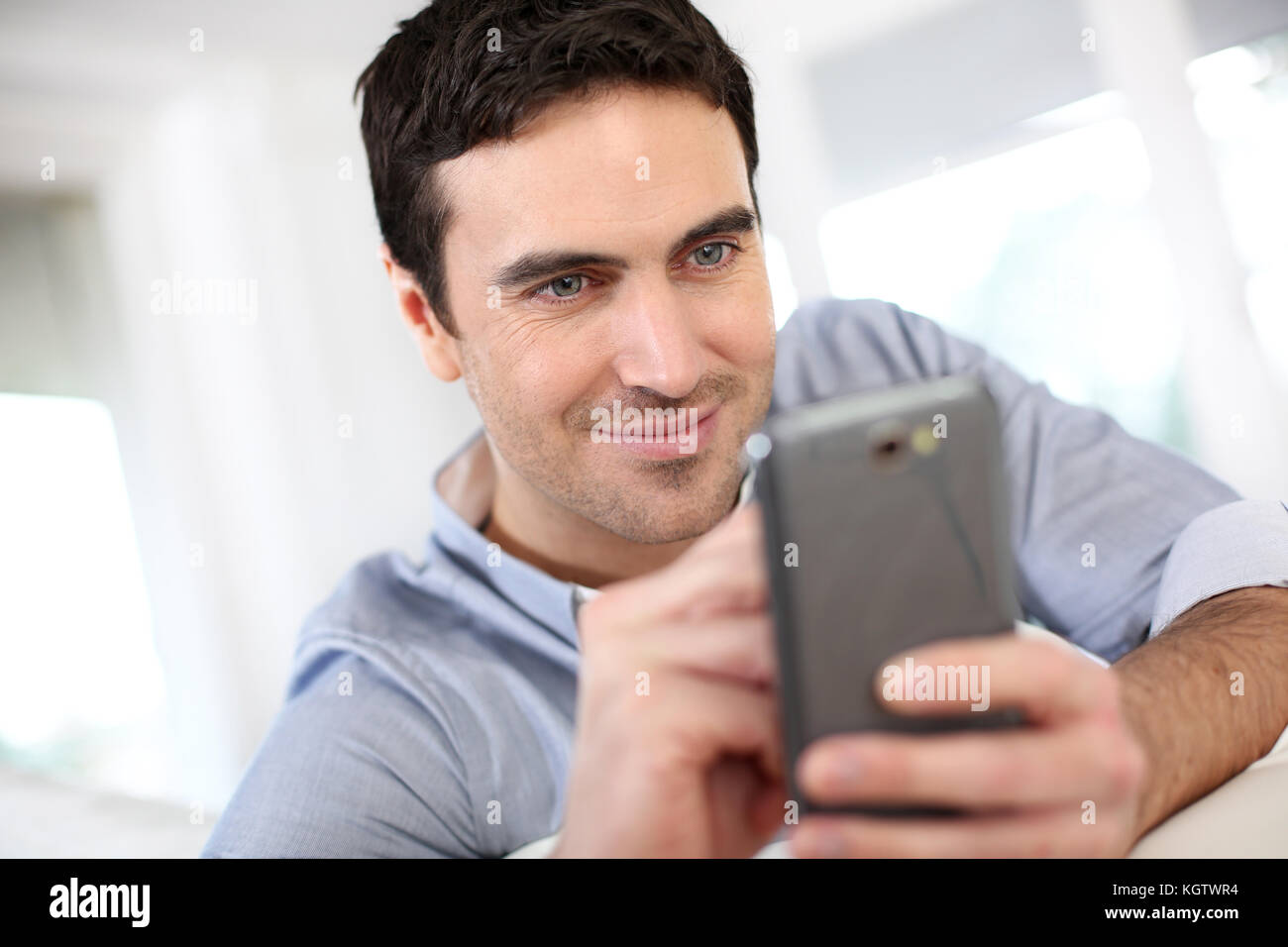 Man at home using smartphone Stock Photo - Alamy