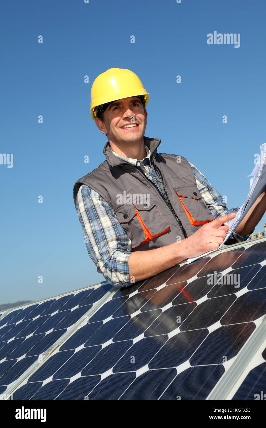 Man standing by solar panels with construction plan Stock Photo - Alamy