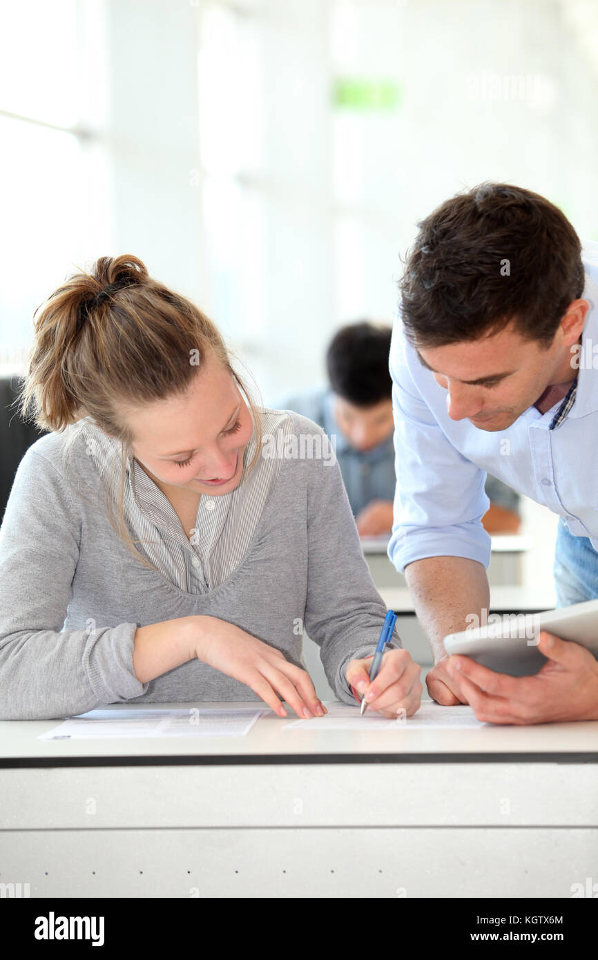 Teacher with student girl writing assignment Stock Photo - Alamy
