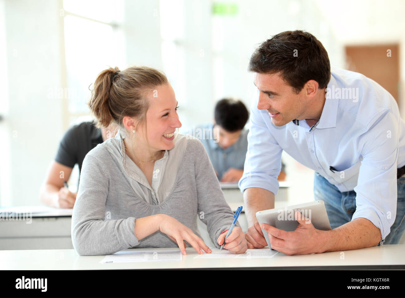 Teacher with student girl writing assignment Stock Photo - Alamy