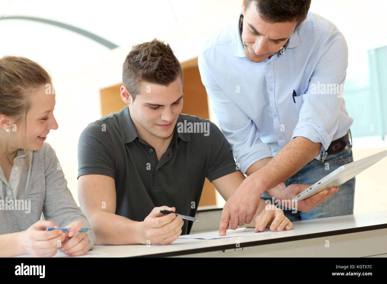 Teacher helping students with assignment Stock Photo - Alamy
