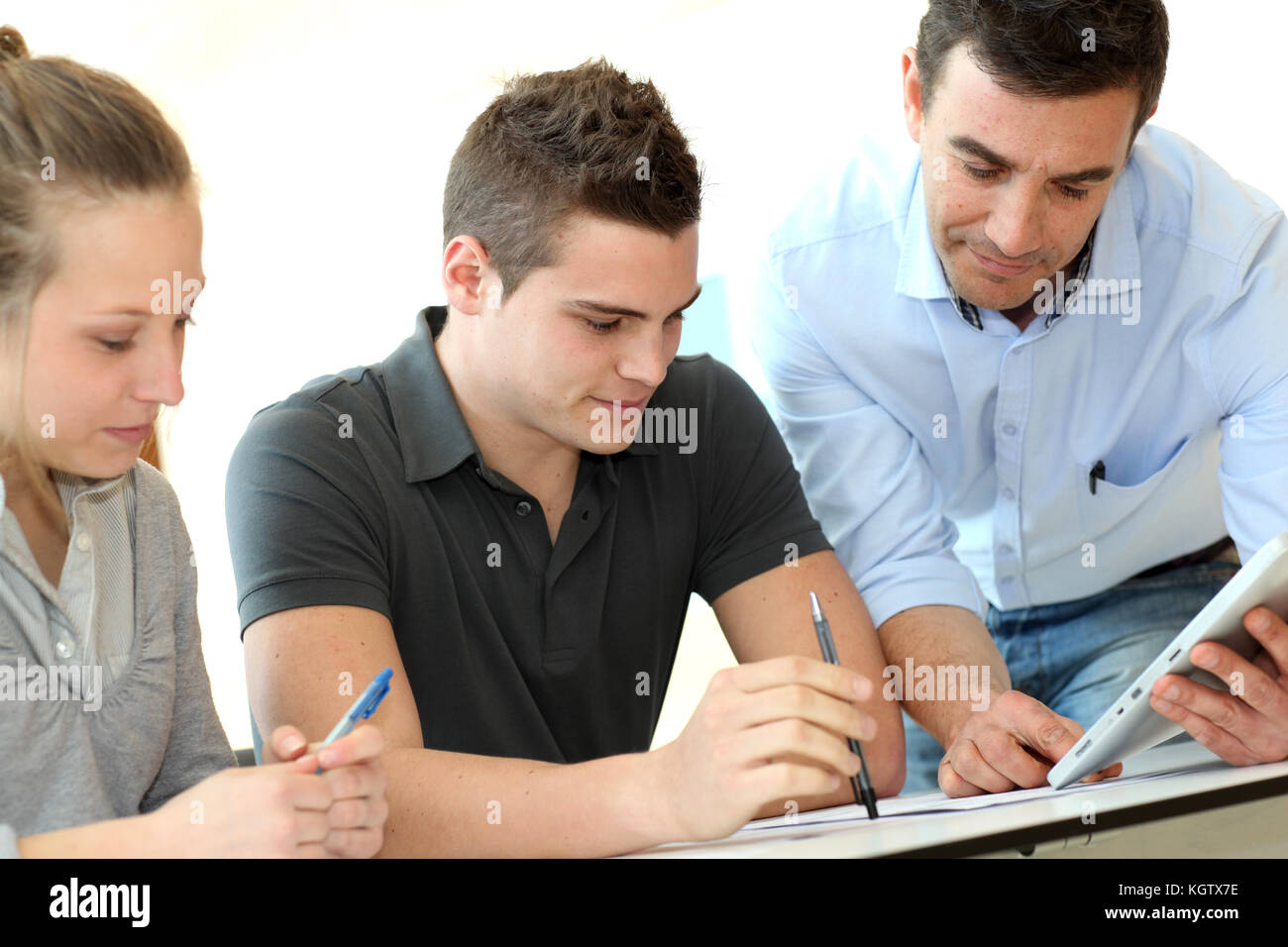 Teacher helping students with assignment Stock Photo - Alamy