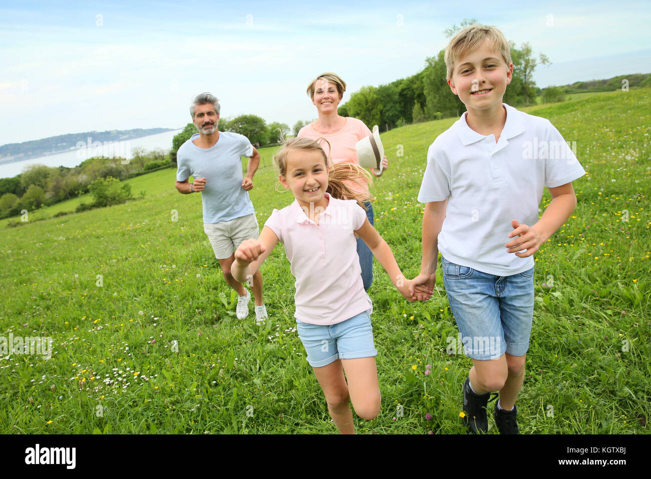Family of four running in countryside Stock Photo - Alamy