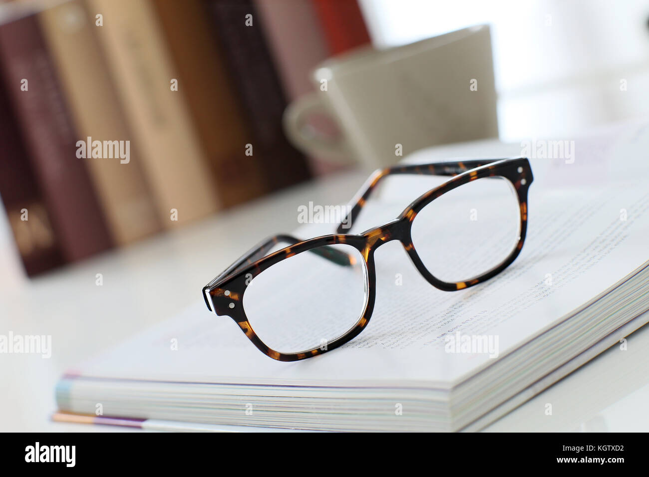 Eyeglasses laid over book on table Stock Photo - Alamy