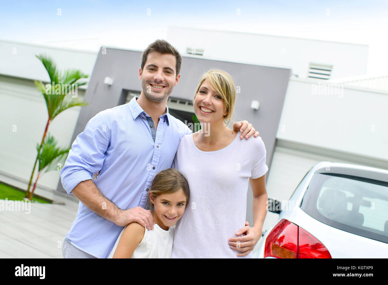 Parents with kid standing in front of new home Stock Photo - Alamy