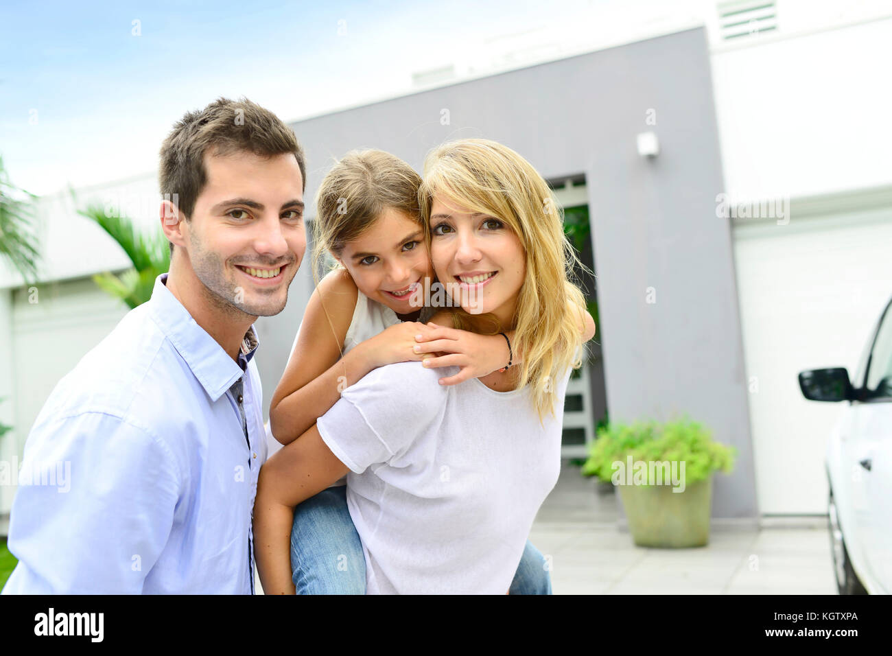 Parents with kid standing in front of new home Stock Photo - Alamy