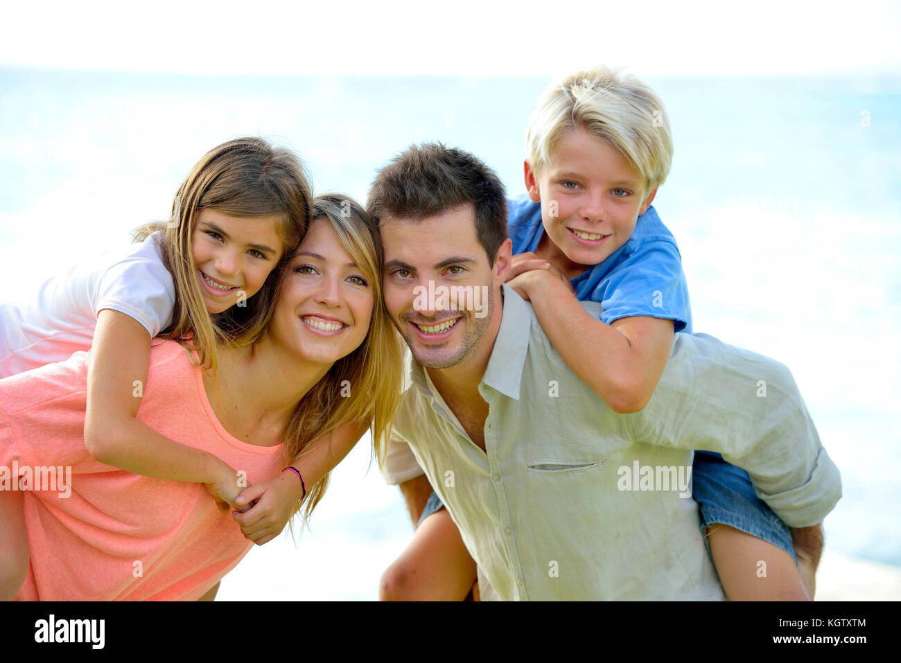 Cheerful parents holding kids on their back Stock Photo - Alamy