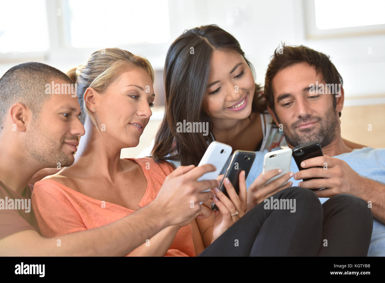 Friends at home playing with smartphones Stock Photo - Alamy
