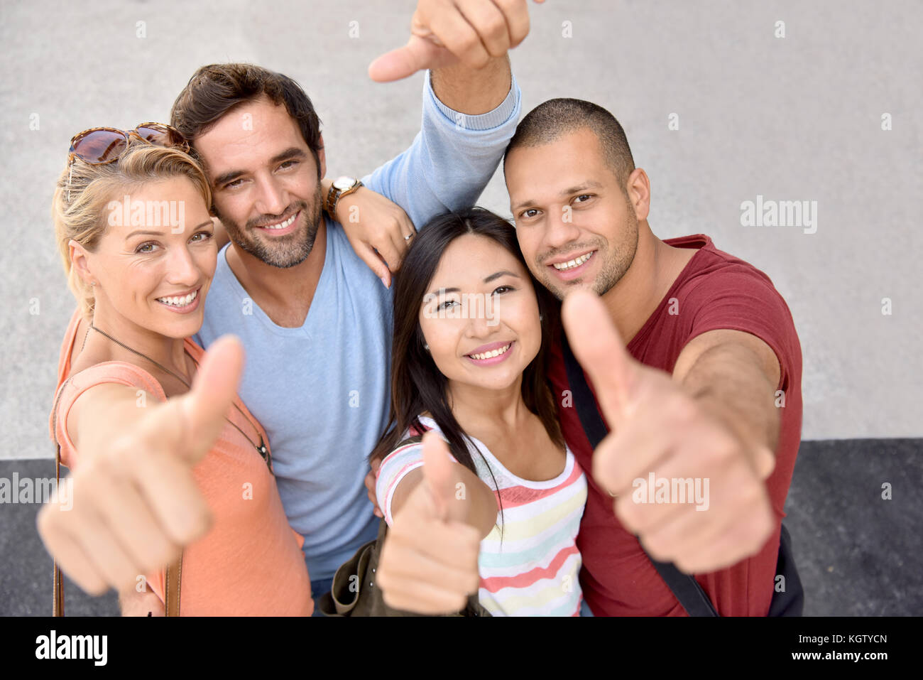 Portrait of four young adults showing thumbs up Stock Photo - Alamy