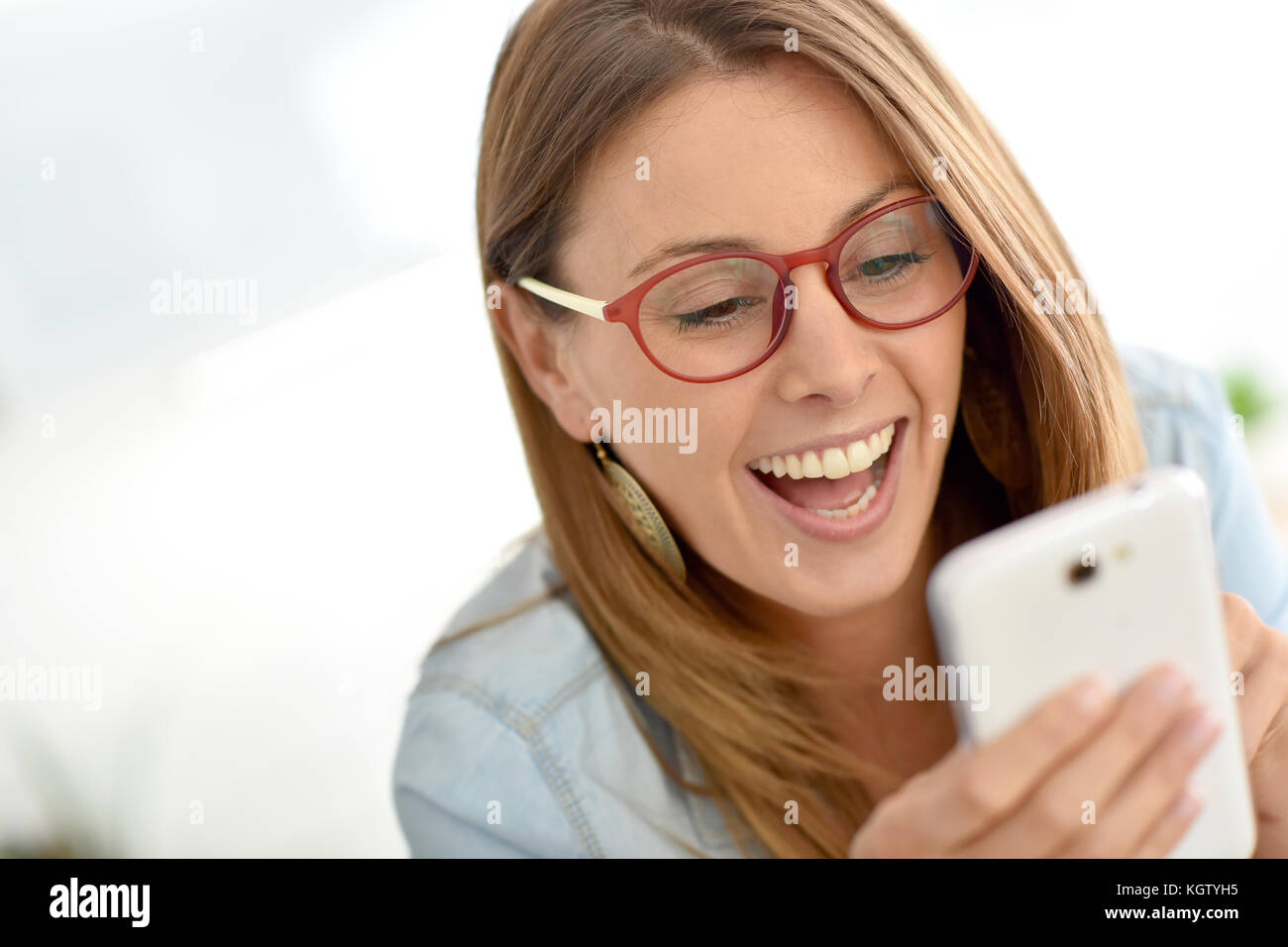 Cheerful girl having fun using smartphone Stock Photo - Alamy