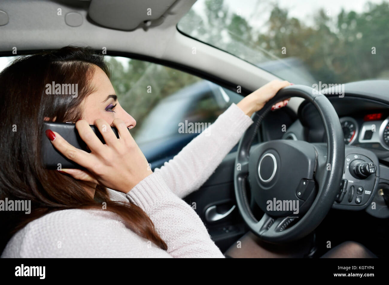 Woman talking on phone while driving Stock Photo - Alamy