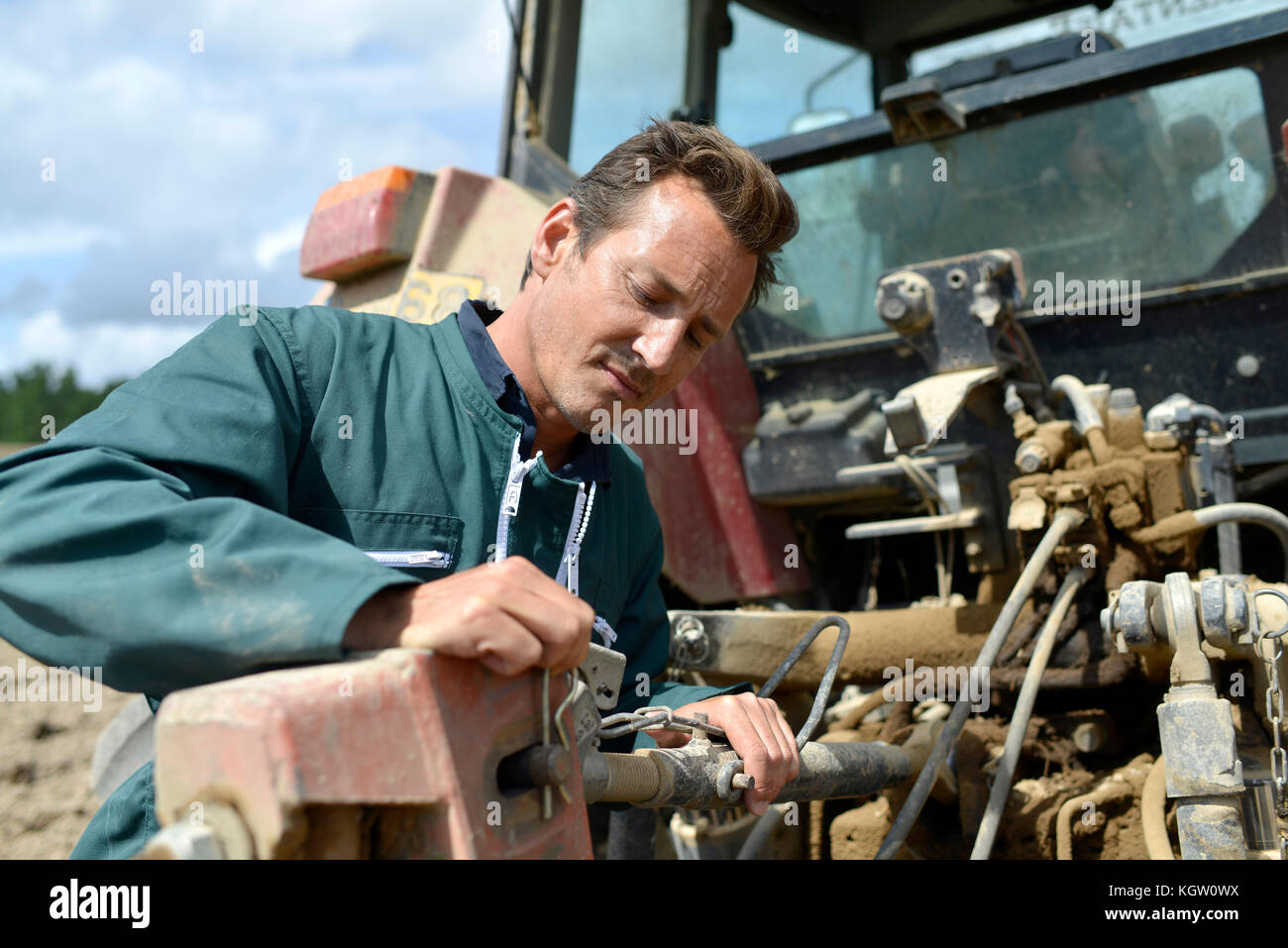 Farmer working on tractor in farming land Stock Photo - Alamy