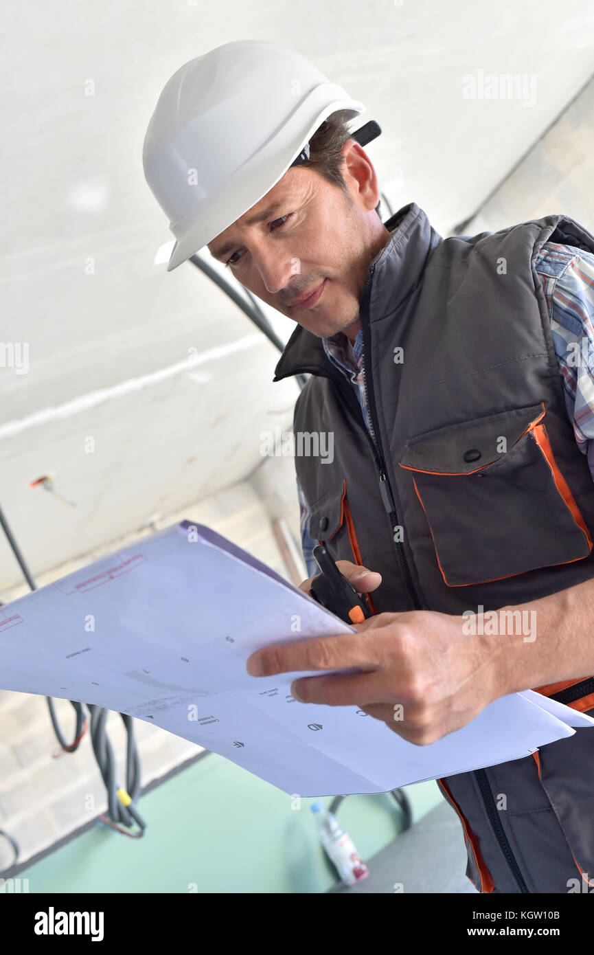 Construction worker checking blueprint on site Stock Photo - Alamy