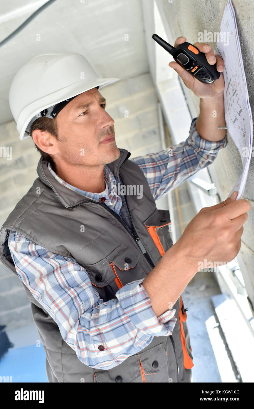 Engineer on building site checking blueprint Stock Photo - Alamy