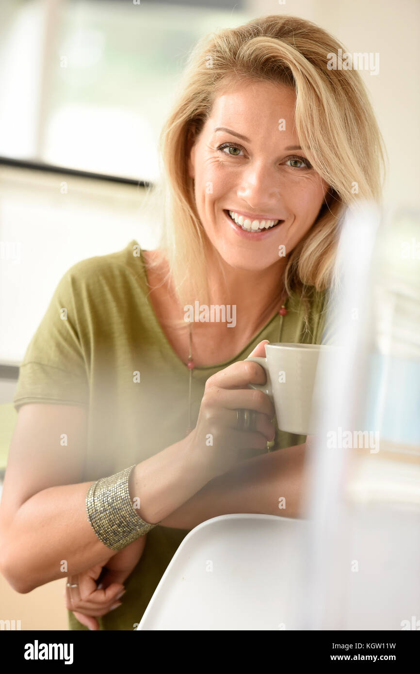 Attractive blond middle-aged woman dinking hot tea Stock Photo - Alamy
