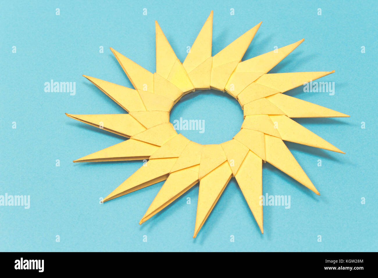 Origami yellow paper sun isolated on blue background Stock Photo - Alamy
